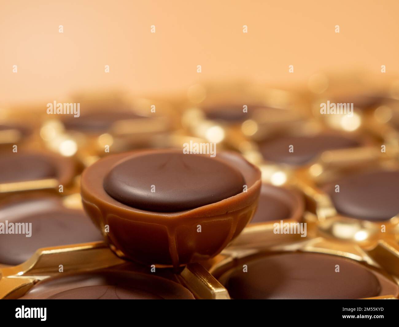Chocolate candies on an orange background. Sweets with caramel. Round ...
