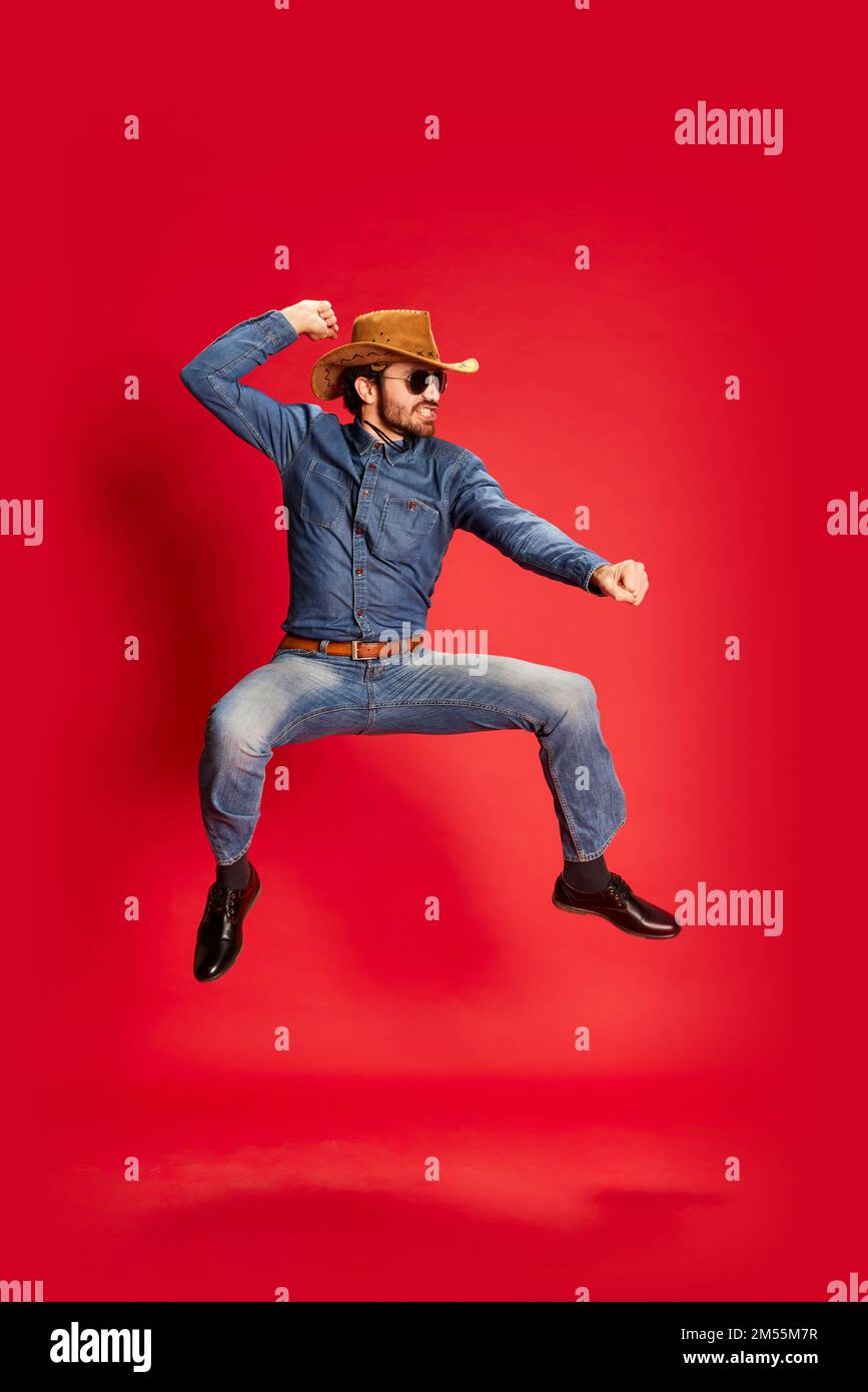 Excited young man in cowboy style outfit having fun, posing isolated ...