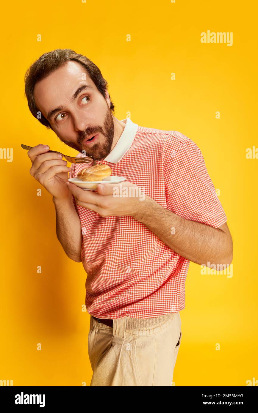 Handsome stylish man with moustache in polo-shirt tasting eclair ...