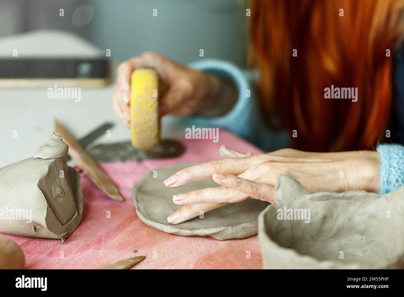 Women's hands knead the clay and sculpt a cup from it. The process of ...