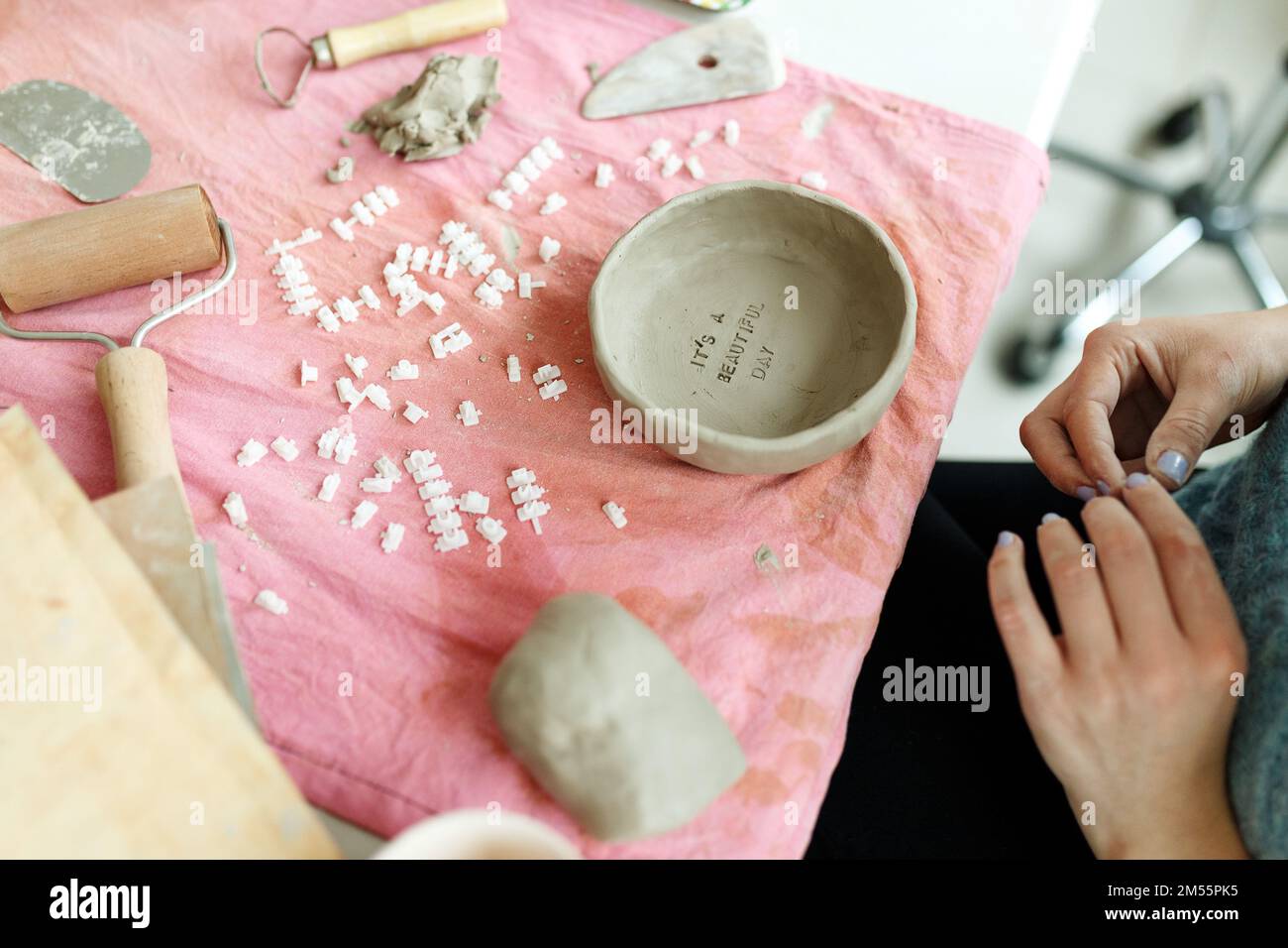 A potter makes an inscription or drawing on a wet clay plate. Concept ...