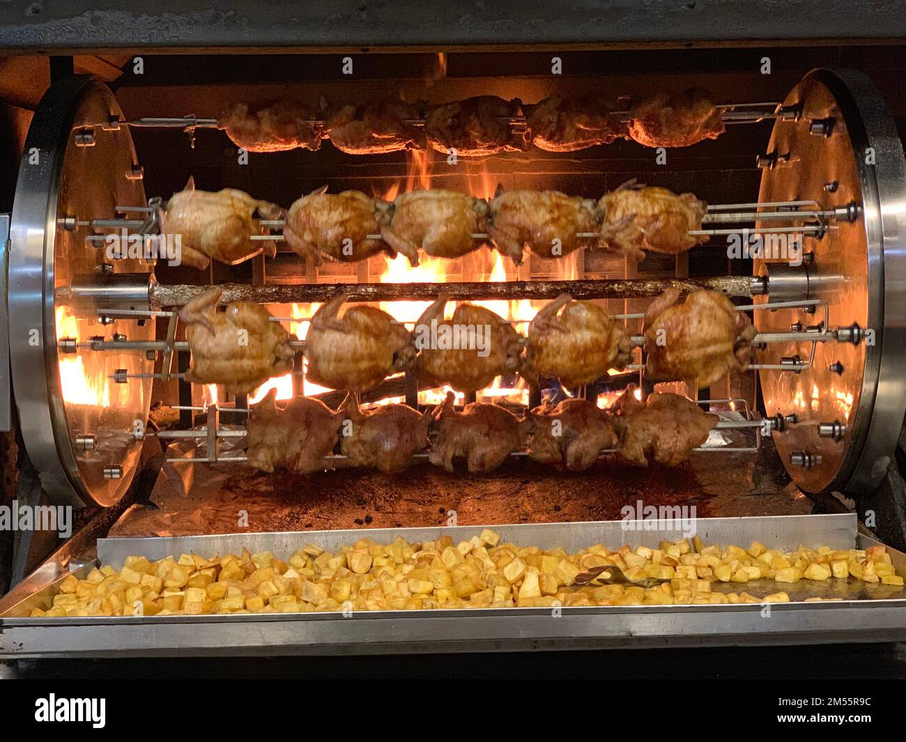 Spit-roasted chickens, chickens on the spit are cooking in an oven ...