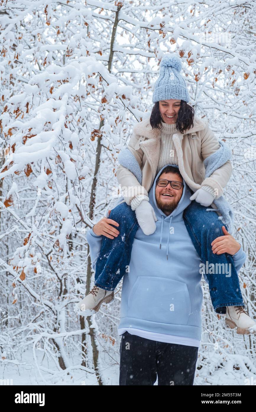 In a snow-covered forest, a woman is piggybacking on a man Stock Photo ...