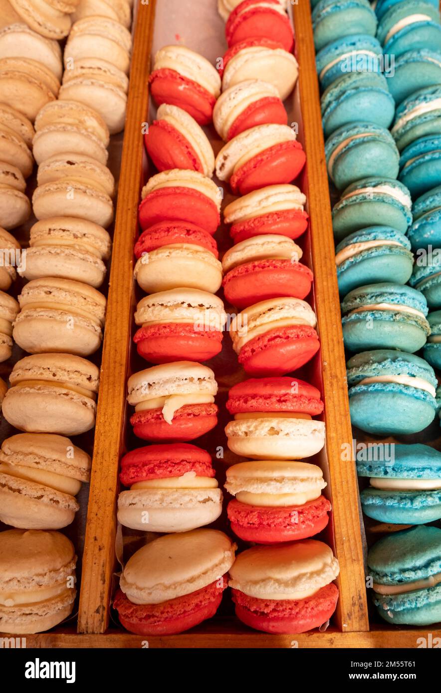 A vertical high-angle view of trays of colorful macarons displayed on a ...