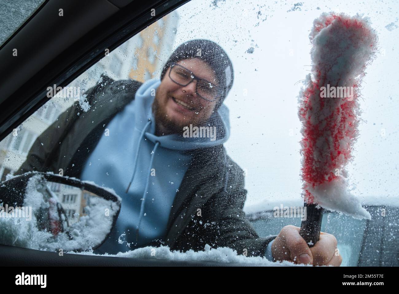 Snowfall is forecast for the winter months, and a man cleans the car ...