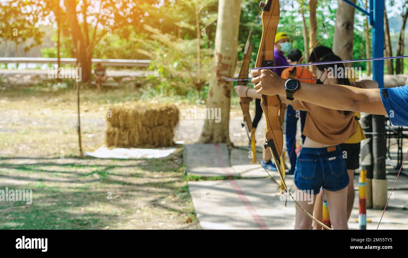 Hands of young man aims archery bow and arrow to colorful target in ...