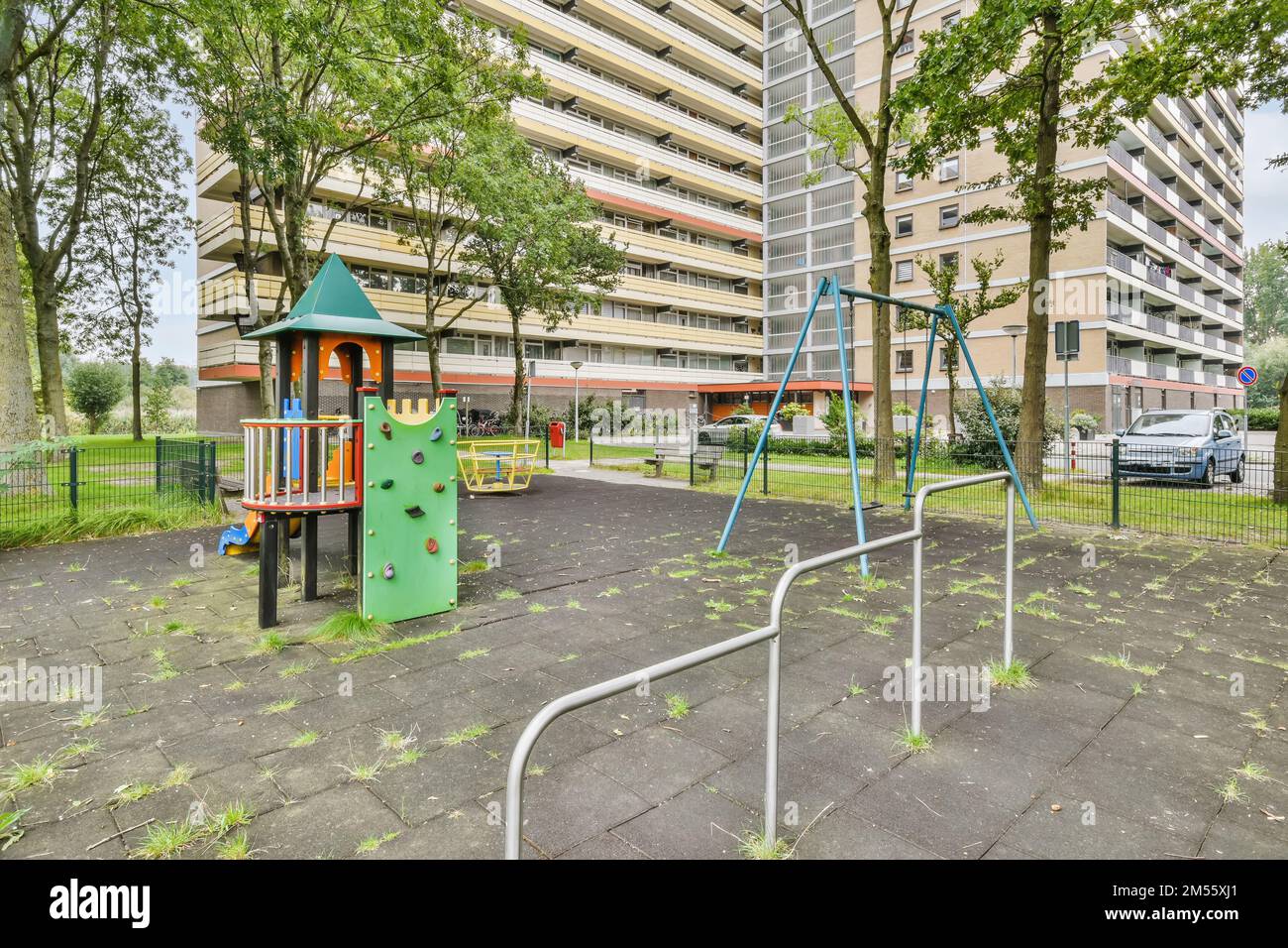 an empty playground in front of a multi - storey apartment building ...