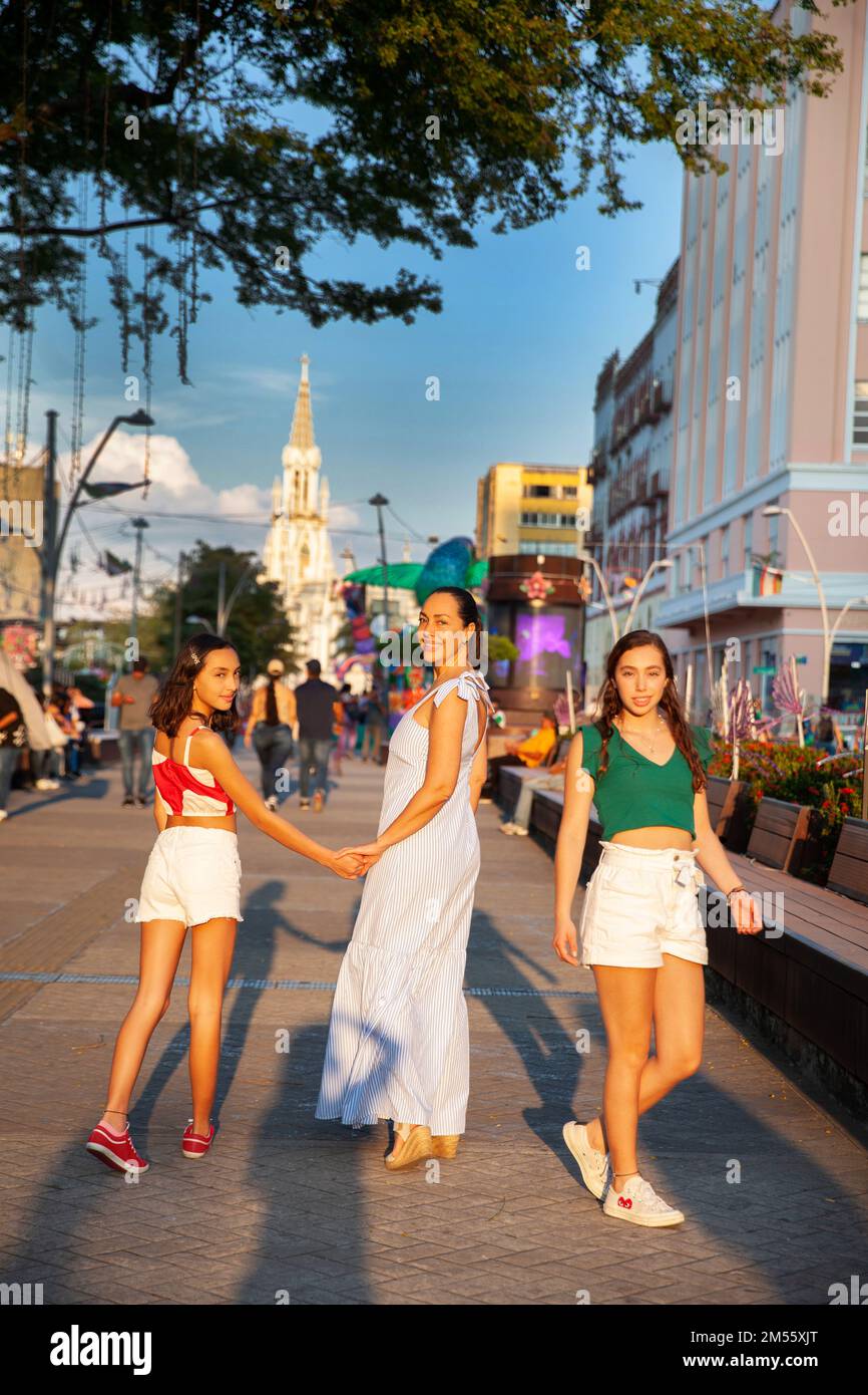 Tourists walking along the Cali River Boulevard with La Ermita church ...