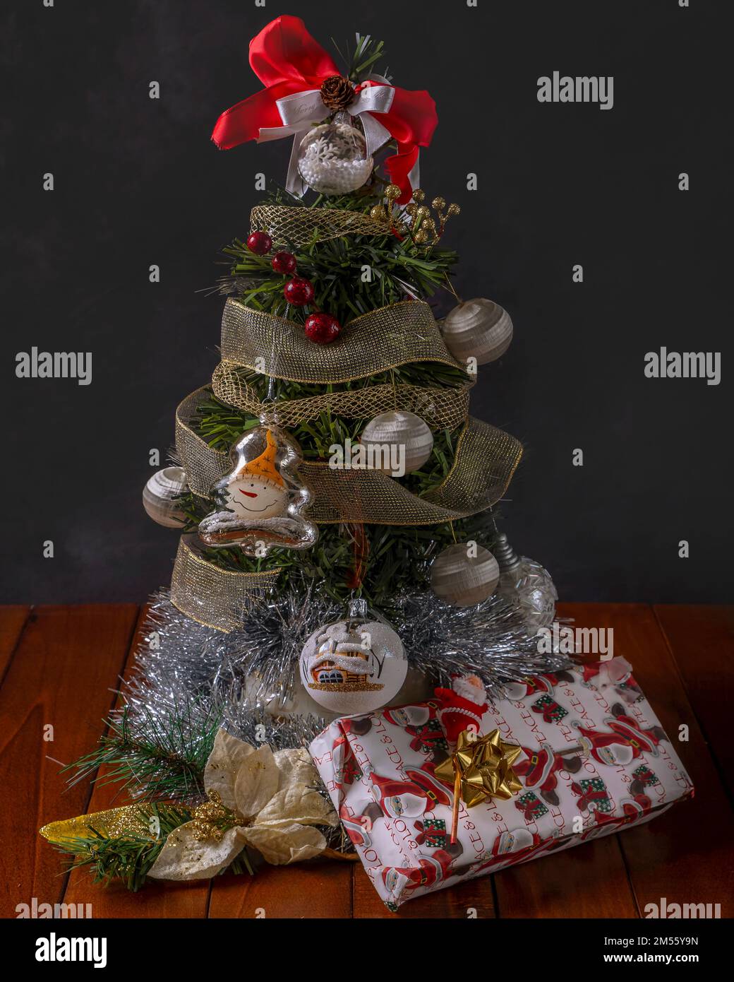 A present is placed under a synthetic Christmas tree decorated with ...