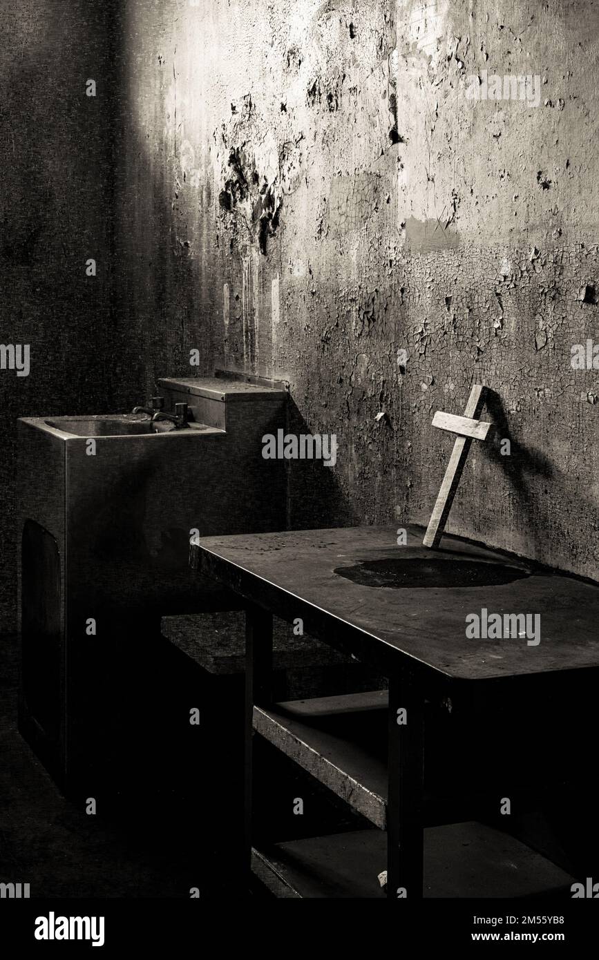 A vertical shot of a wooden Christian cross and a cellmate metal sink ...
