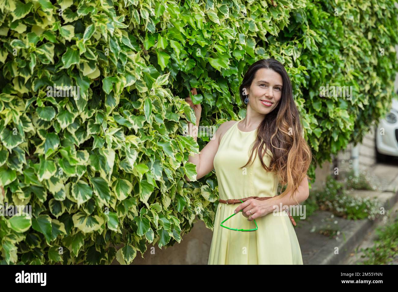 Woman staying surrounded by lush green plants, touching leaves Stock ...