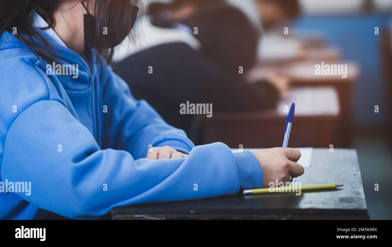 University student holding pen or pencil writing on paper answer sheet ...