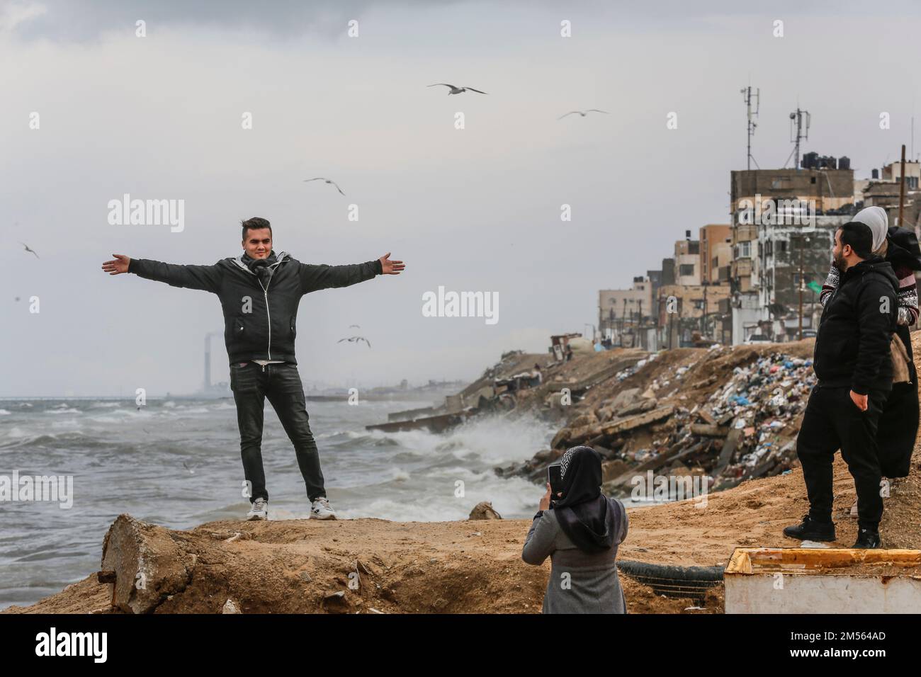 Palestinian youths take pictures near the Gaza shore during heavy rain ...