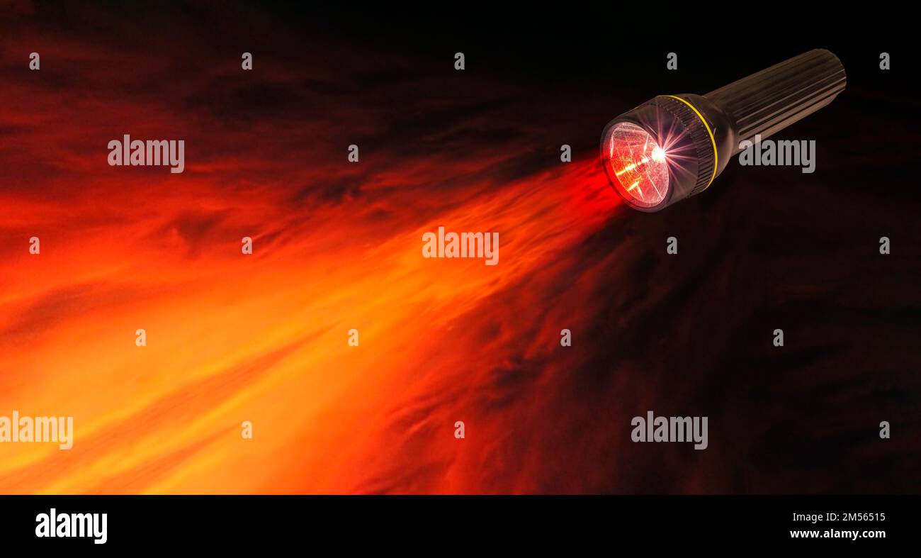 Black flashlight switched on and sending a beam onto a red and yellow ...