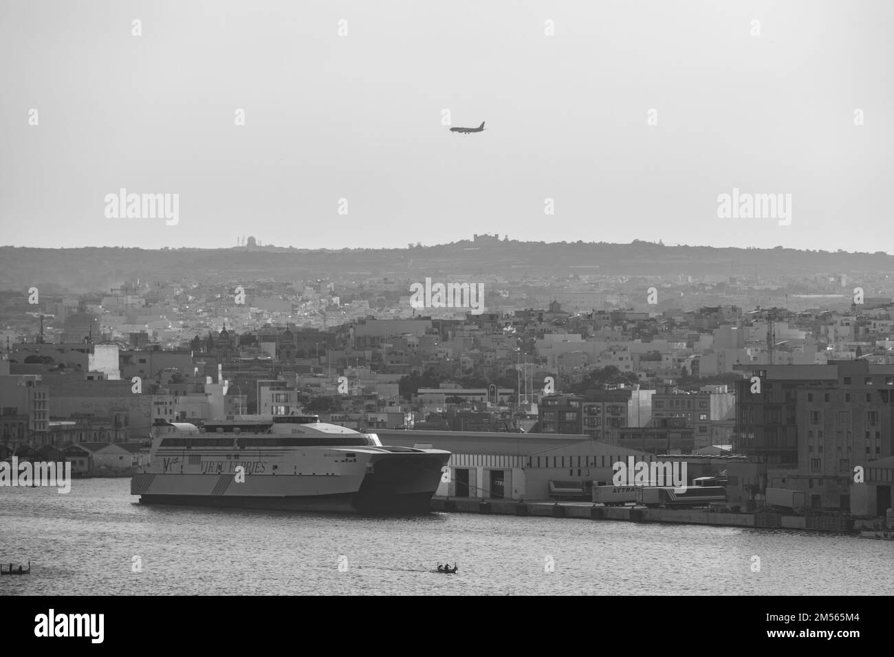 A greyscale of a port with numerous building on the background and a ...