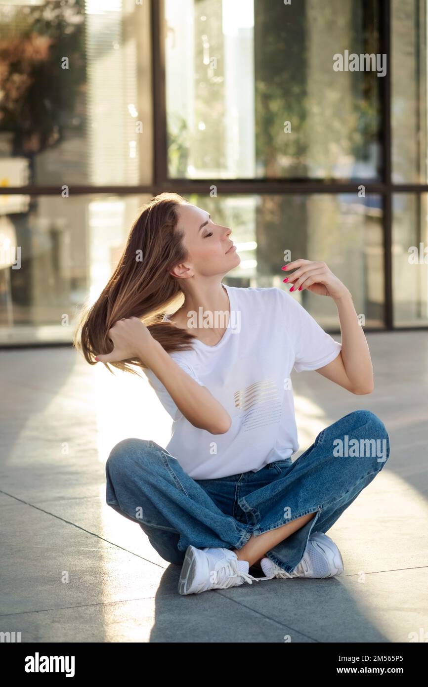 Middle age woman sitting on floor in urban city,wearing casual clothes ...