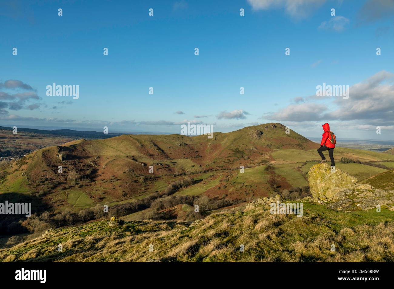 A line female hill walker looks towards Caer Caradoc, a hill in ...
