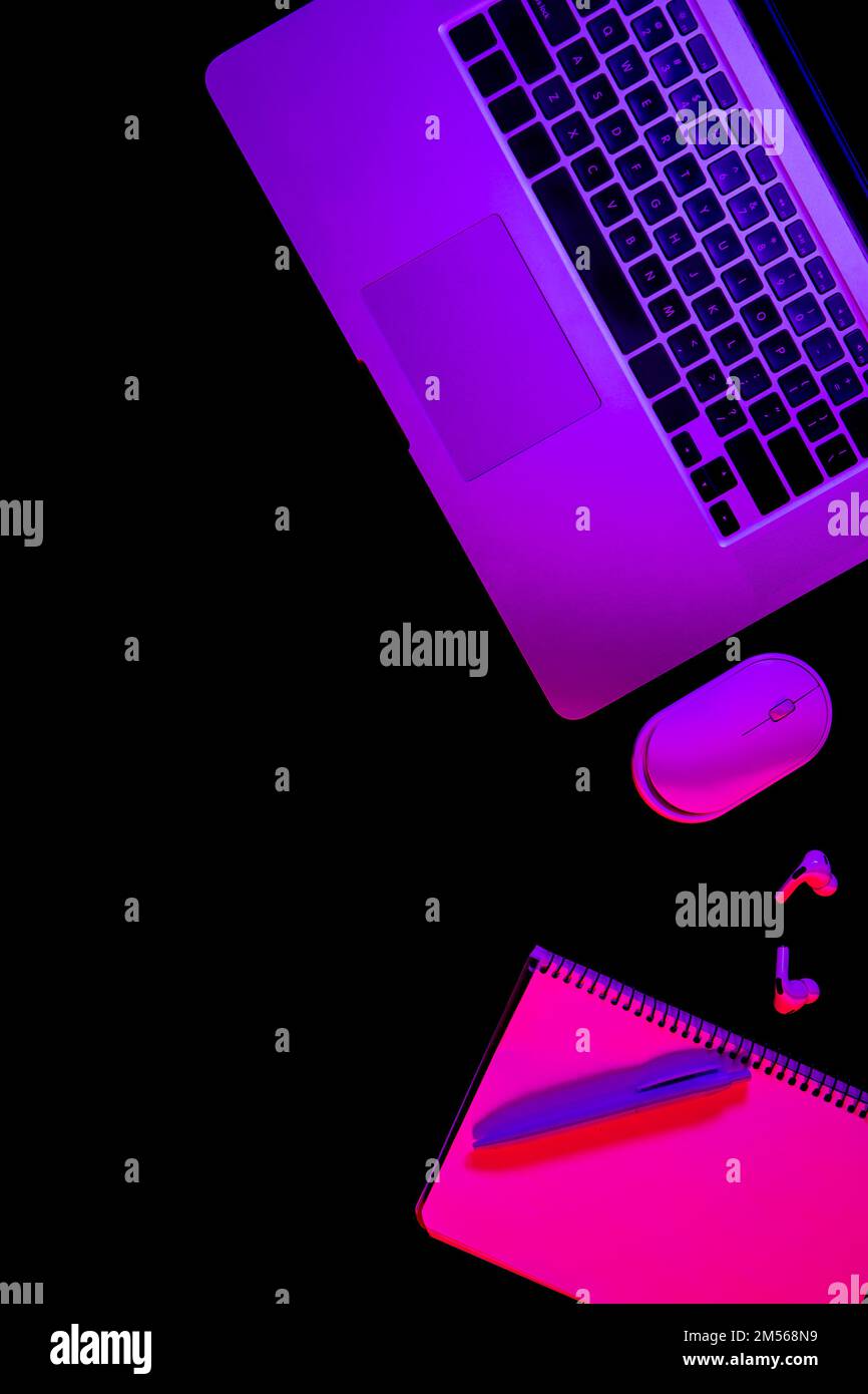 Laptop and notepad on black background with neon light, flat lay Stock ...