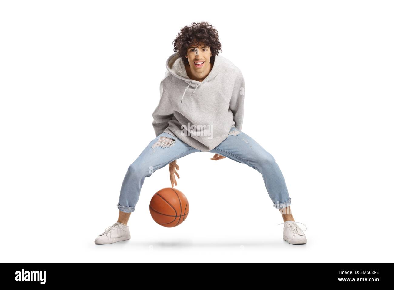 Cheerful guy performing tricks with a basketball isolated on white ...