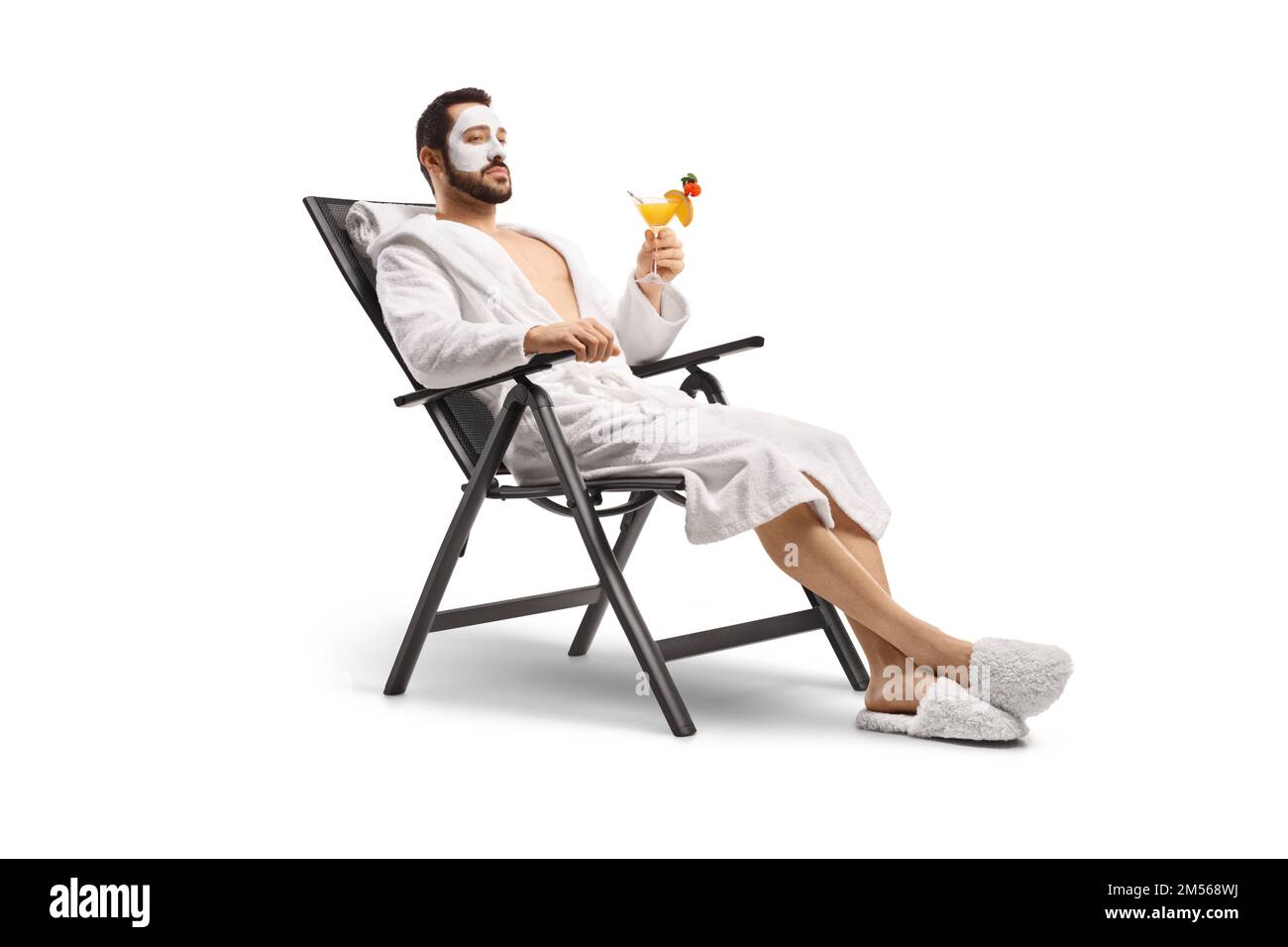 Man in a bathrobe with a face mask sitting on chair with a cocktail ...