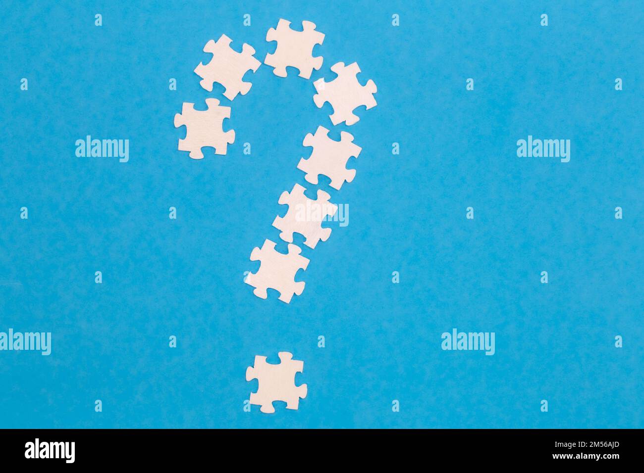 White puzzles in the shape of a question mark on a blue background ...