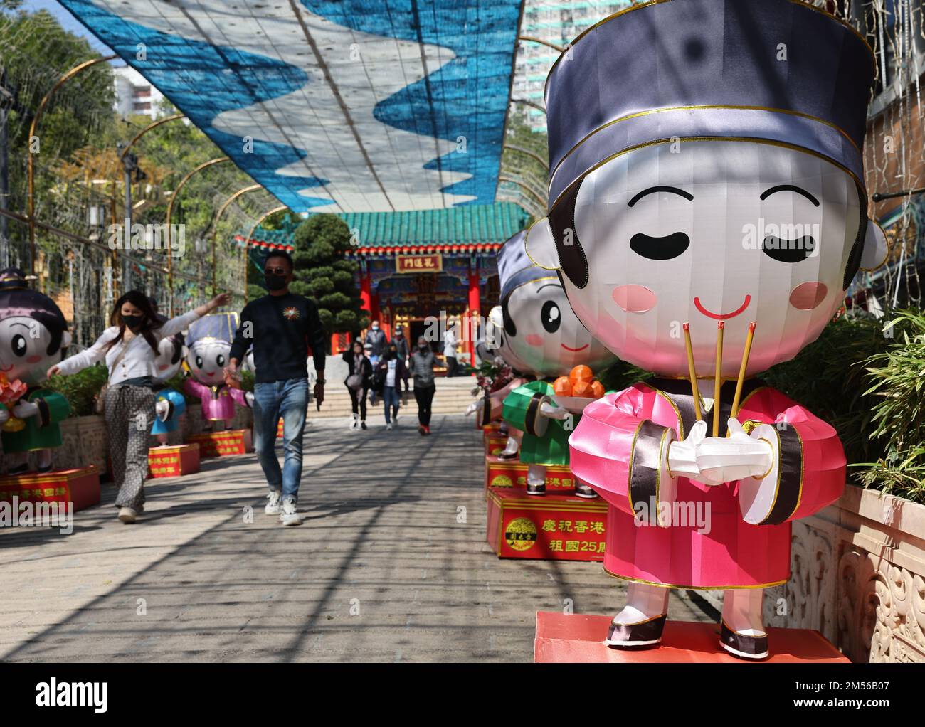 People walk past Taoist priest figures at Wong Tai Sin Temple. 21DEC22 ...