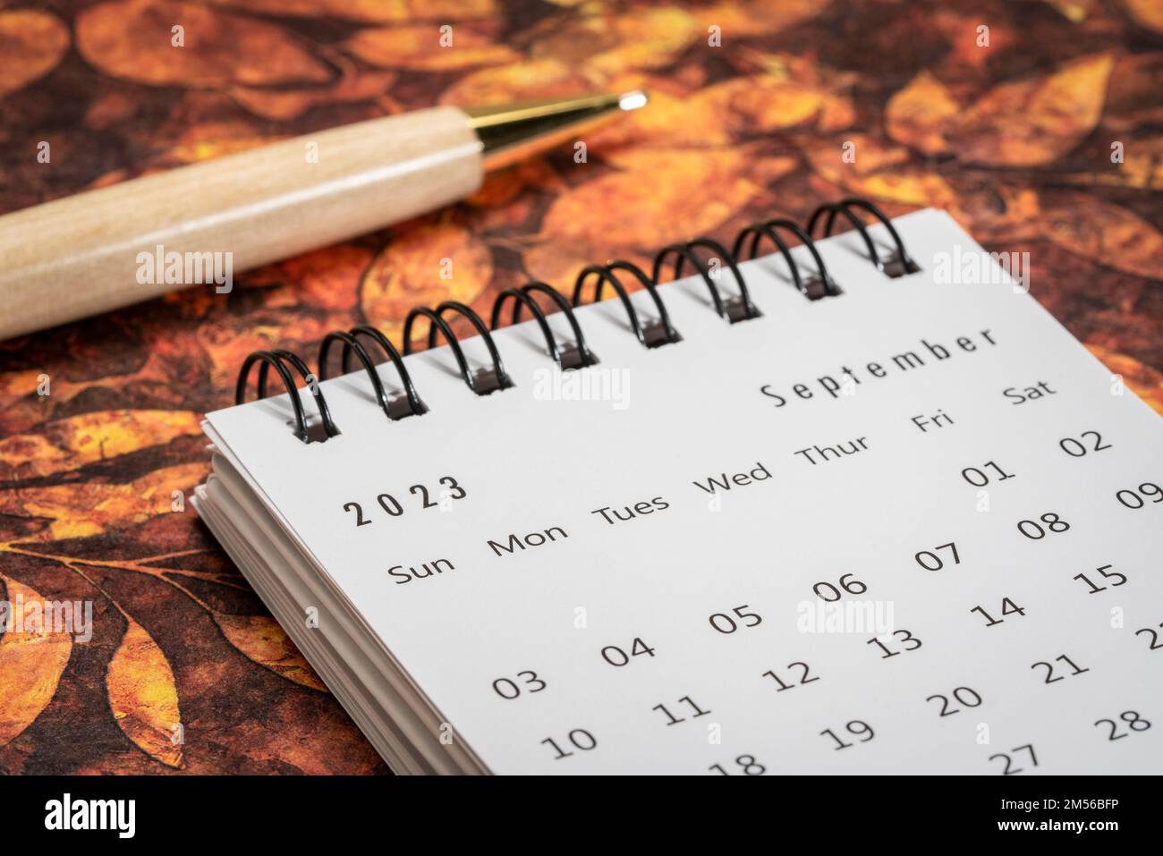 September - small spiral desktop calendar with a stylish pen against ...