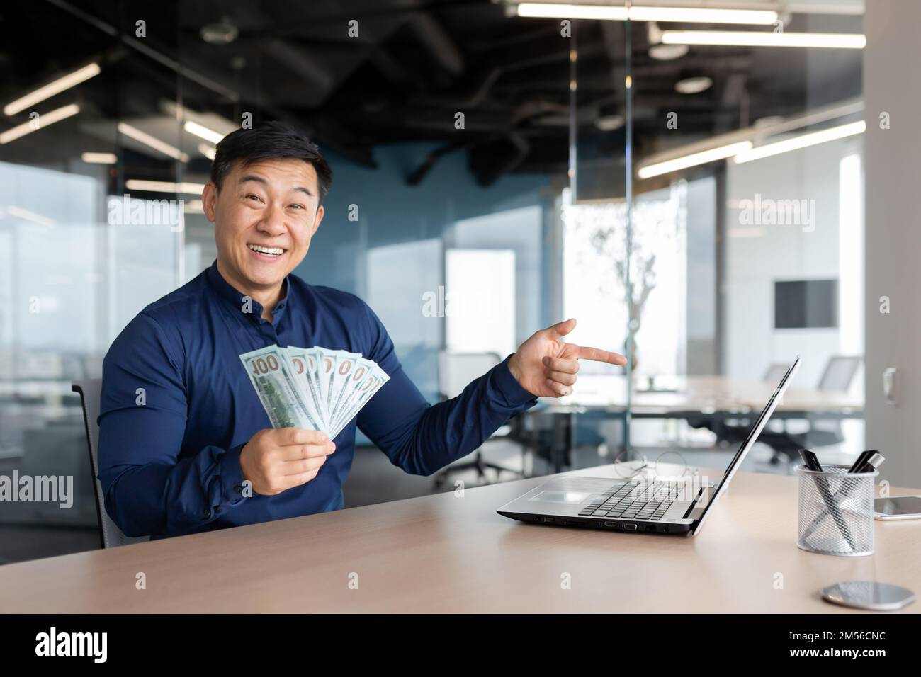 Happy young man Asian businessman sitting in the office holding cash ...