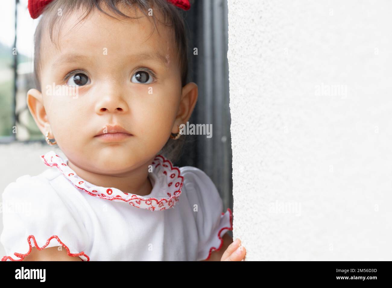 dark-haired baby, with curious look. girl looking distrustful. standing ...