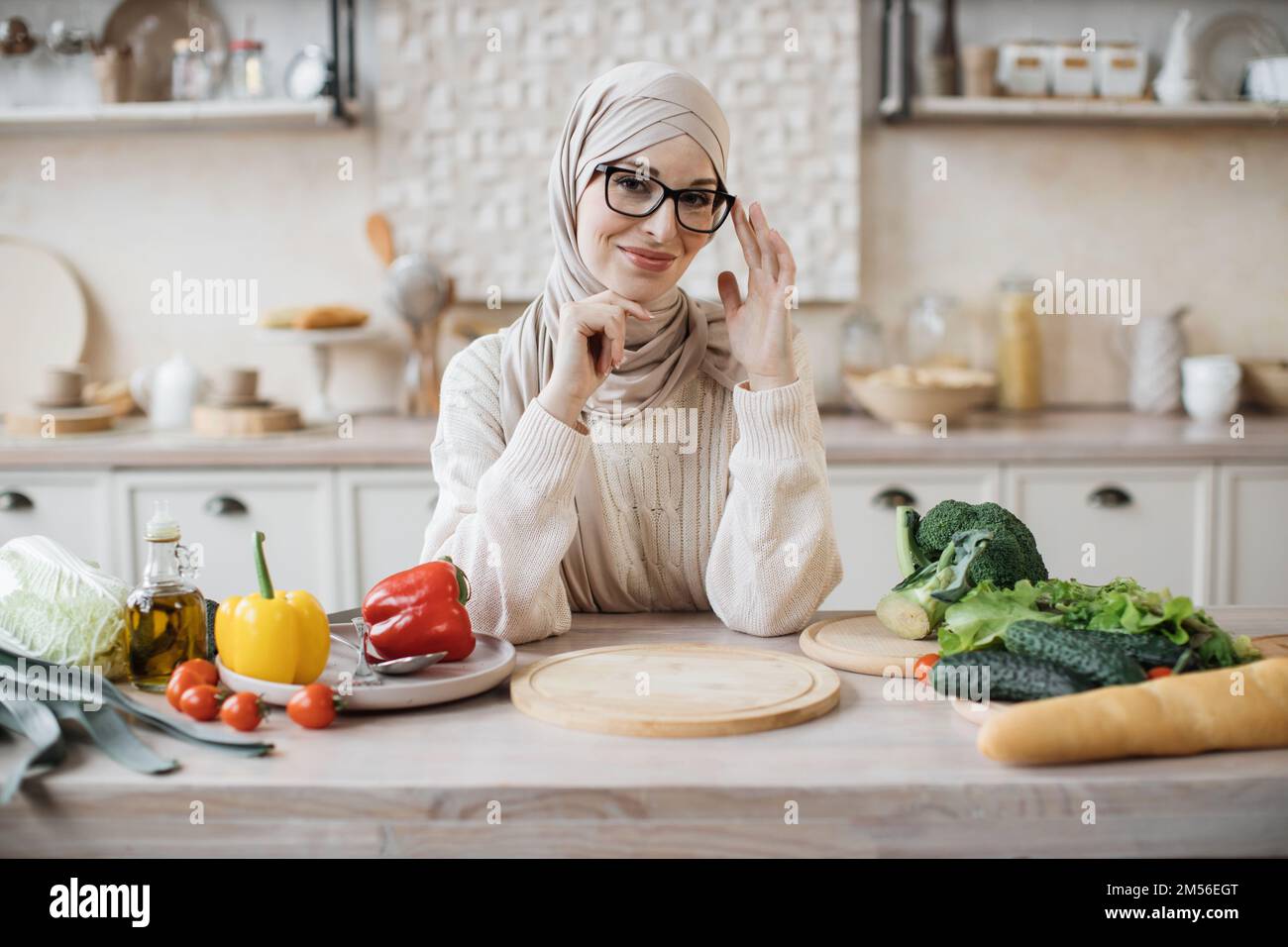 Young smiling muslim woman in hijab sitting at table with fresh ...