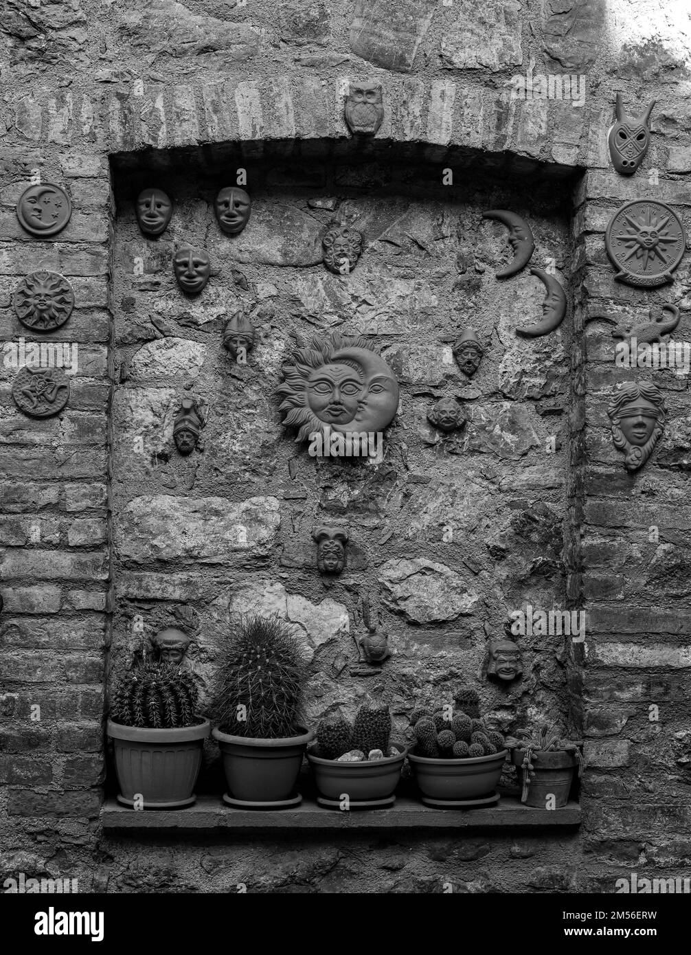 A spiritual corner with astrological carvings on a wall and cacti in a ...