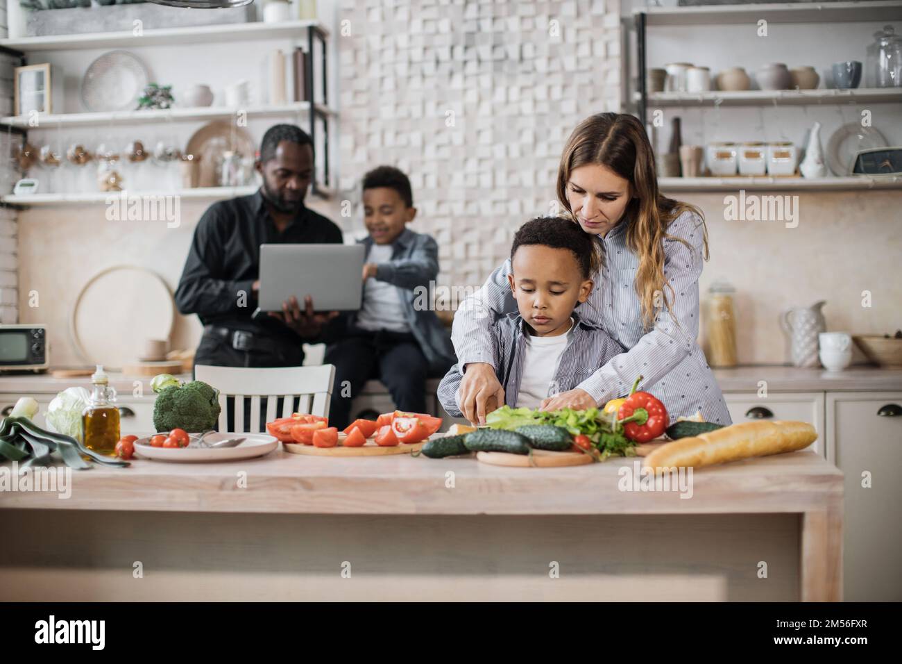 Pretty mother and son preparing tasty food at kitchen. Mommy teaching ...