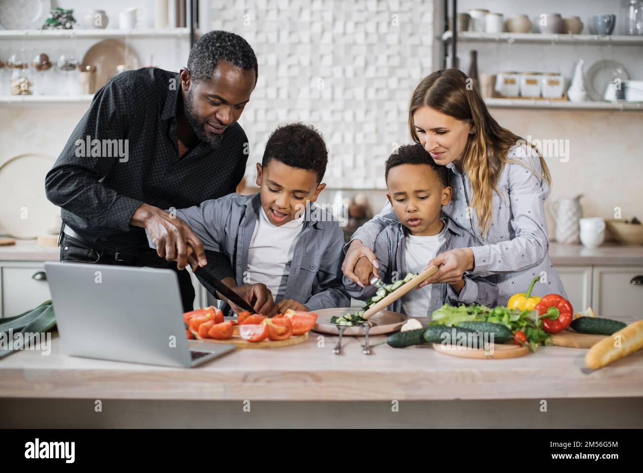 Happy african cute little sons and their young parents having online ...