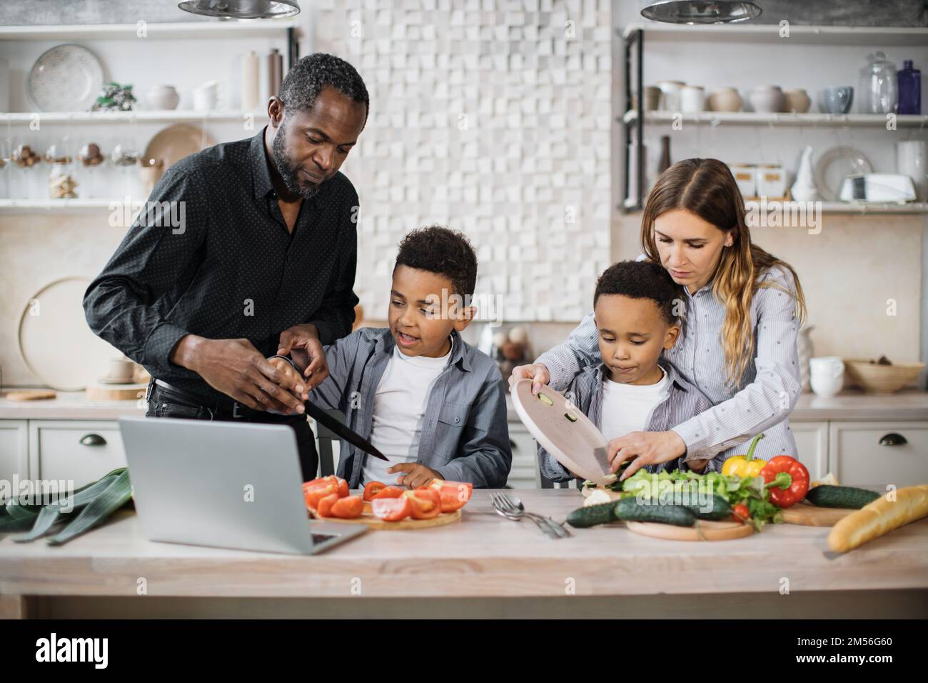 Happy african cute little sons and their young parents having online ...