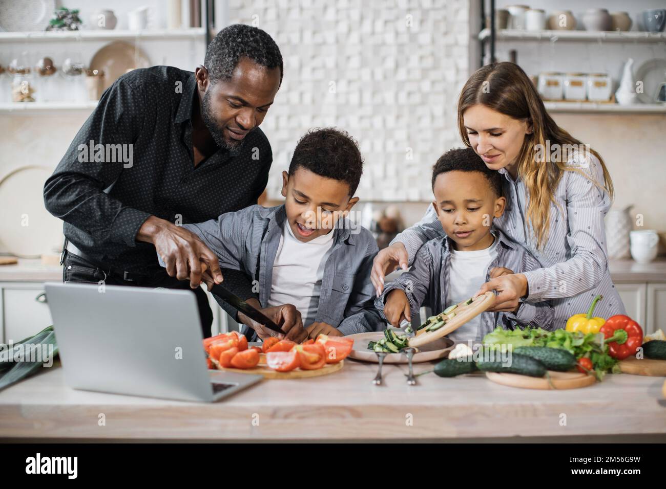 Happy african cute little sons and their young parents having online ...