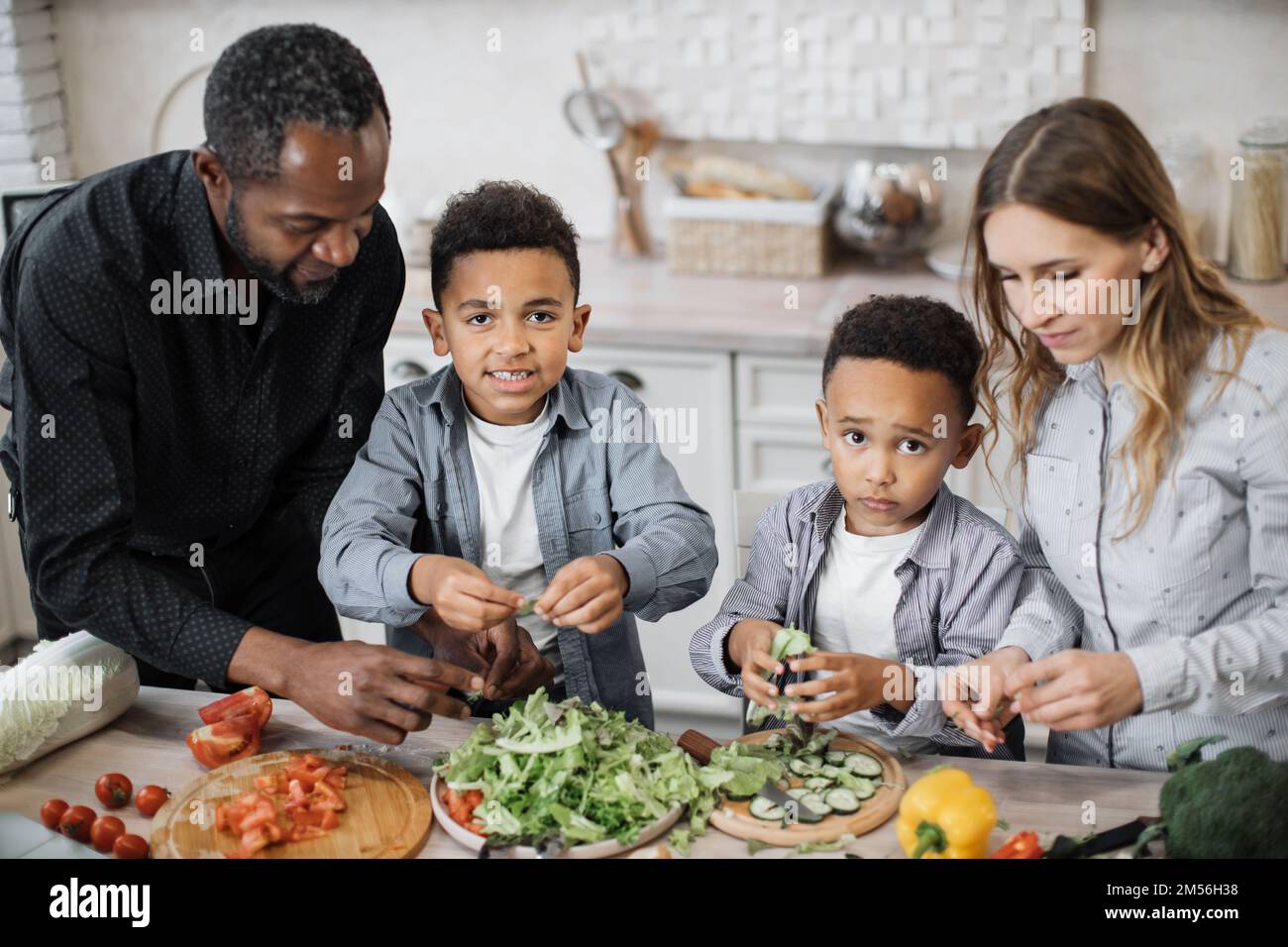 Closeup of smiling boys children helping mom and dad with dinner or ...