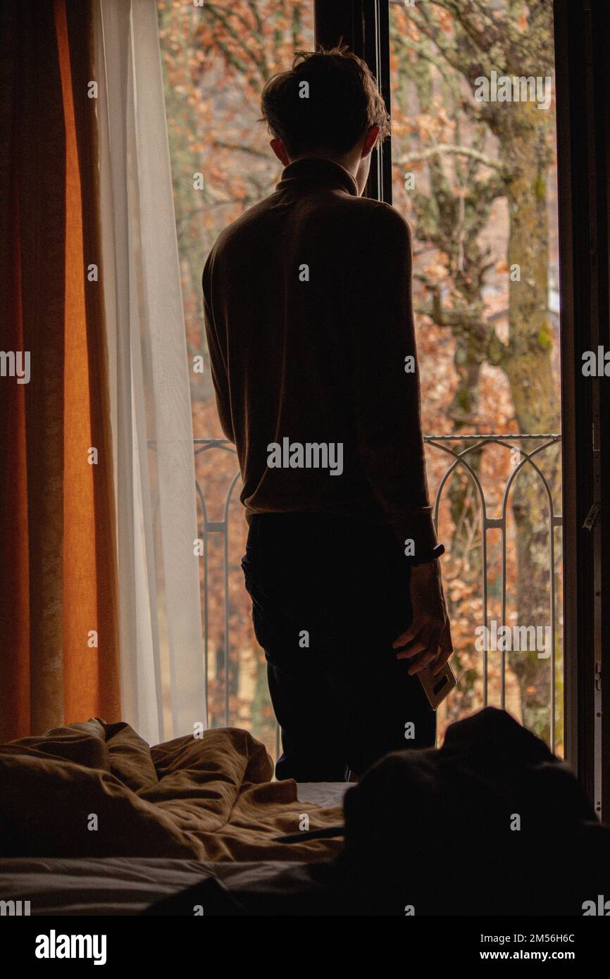 A young guy looking out the window Stock Photo - Alamy