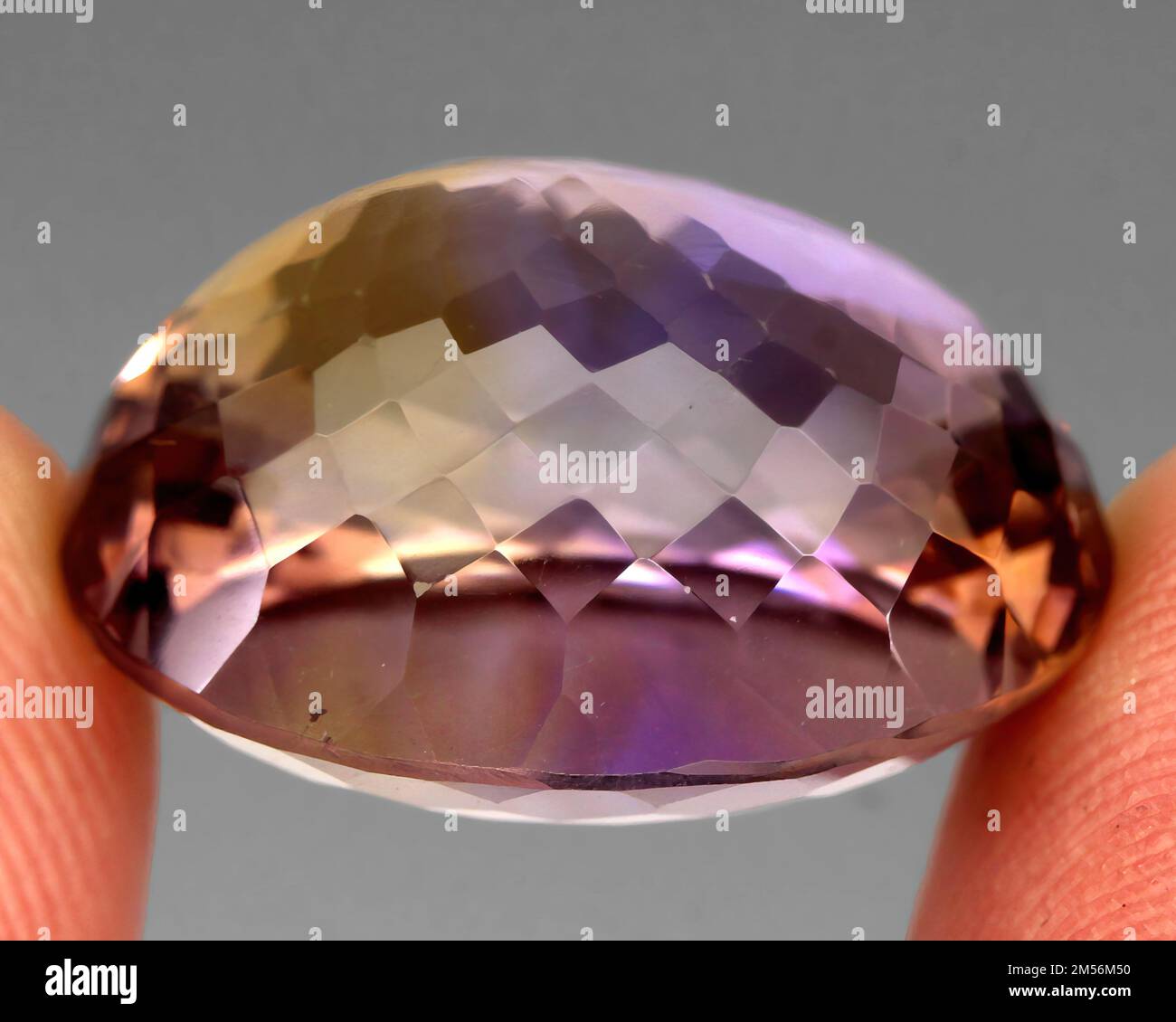 Natural stone bi color ametrine on gray background Stock Photo - Alamy