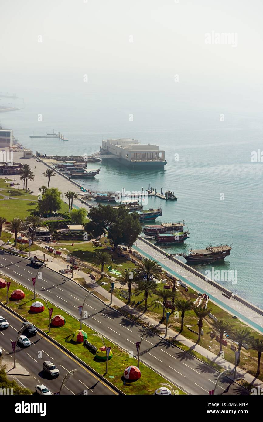 An aerial view of boats by the harbor and lush green palm trees in Doha ...