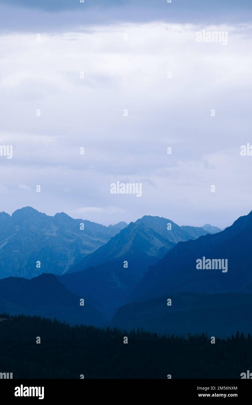 The layers of a mountain range in shades of blue, vertical Stock Photo ...