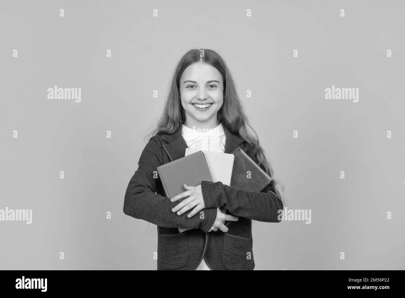 happy tween girl hold school workbook on yellow background, school ...
