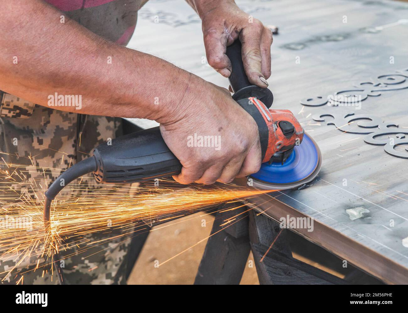 worker scrapes welding welds off metal workpiece with an angle grinder ...