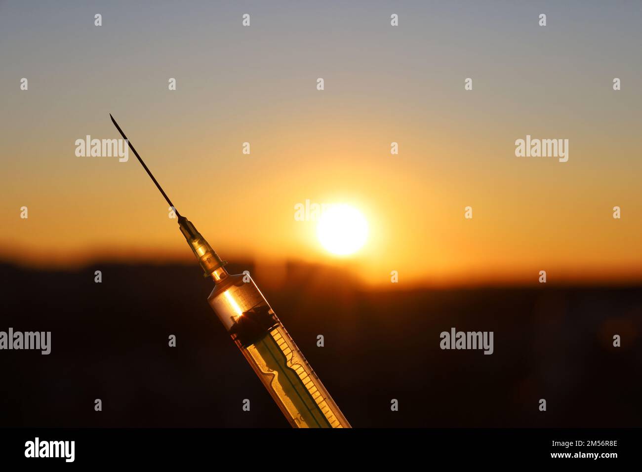 Silhouette of medical syringe on background of sunset in city. Concept ...