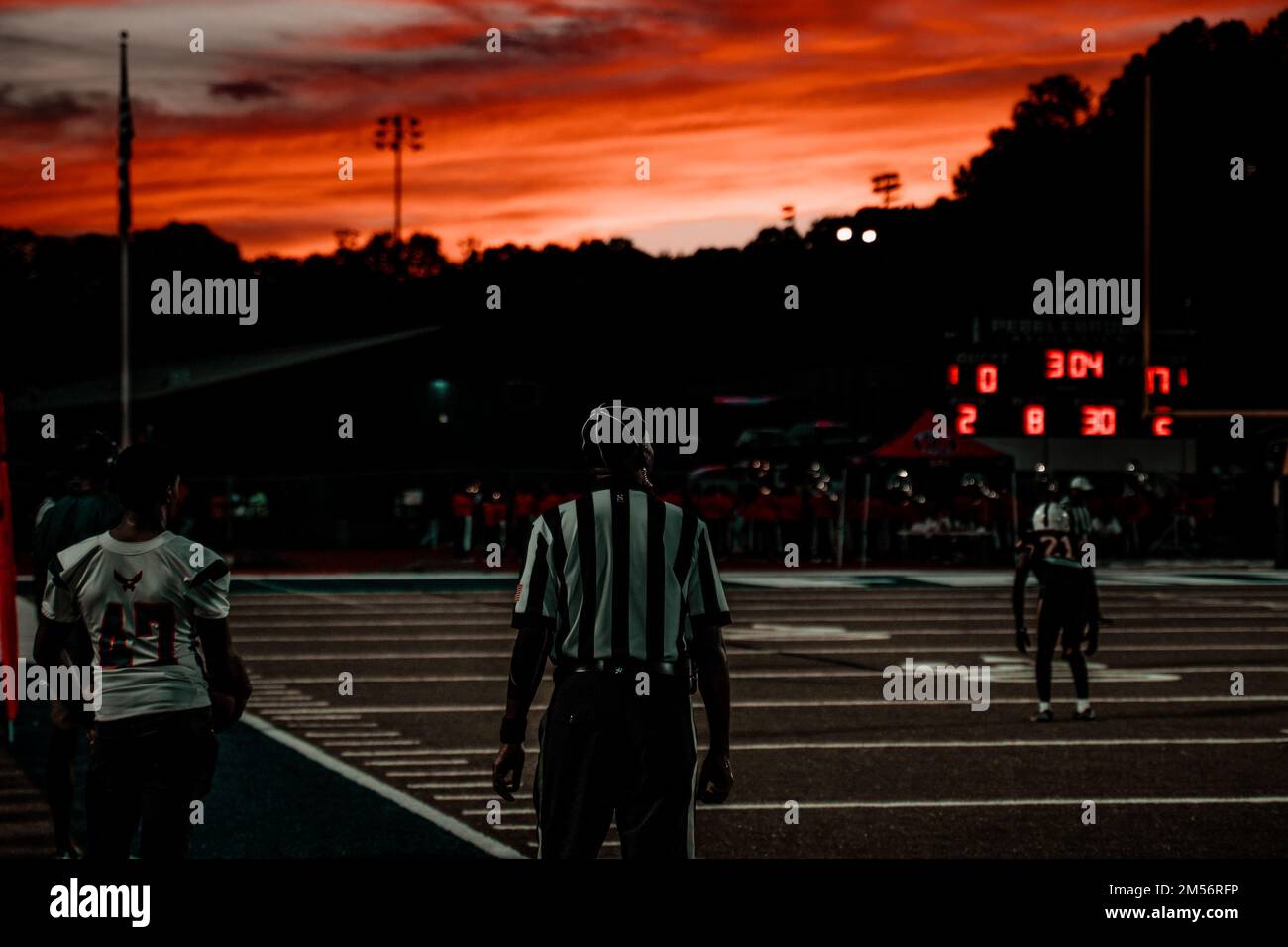 A group of athletes playing football at scenic orange sunset outdoors ...