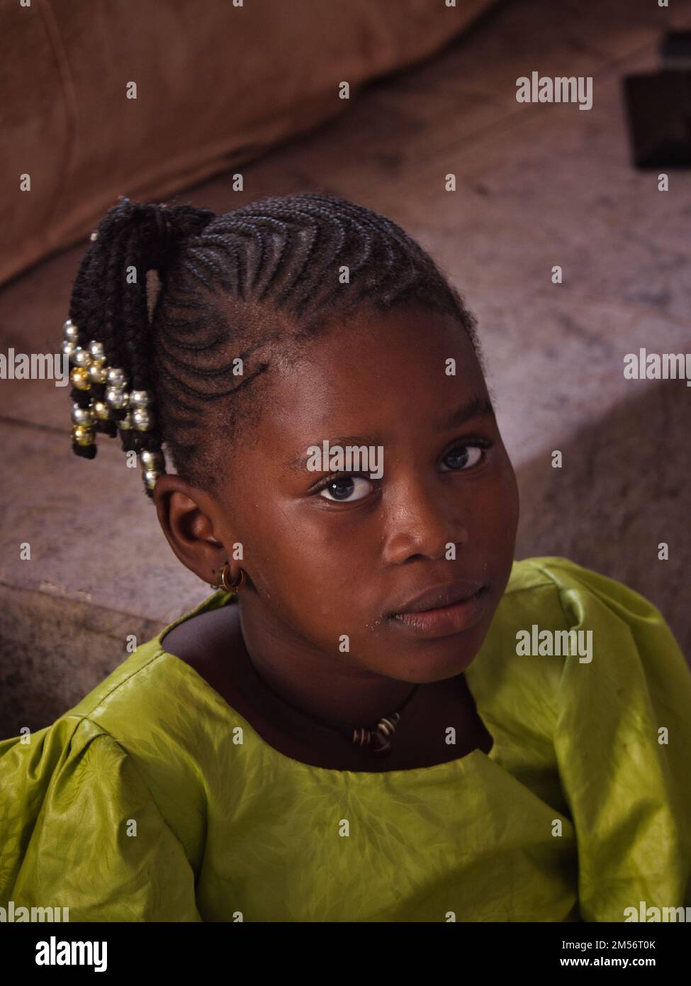 A portrait of an African kid with beautiful hairstyle sitting on the ...