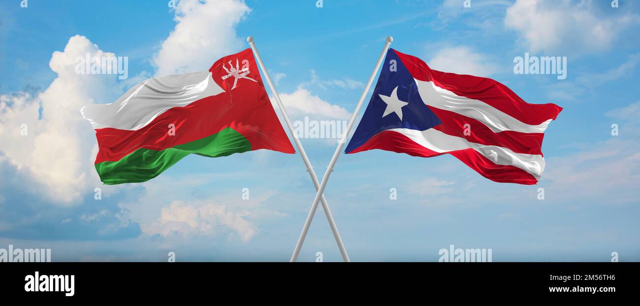 two crossed flags Puerto Rico and Oman waving in wind at cloudy sky. Concept of relationship ...