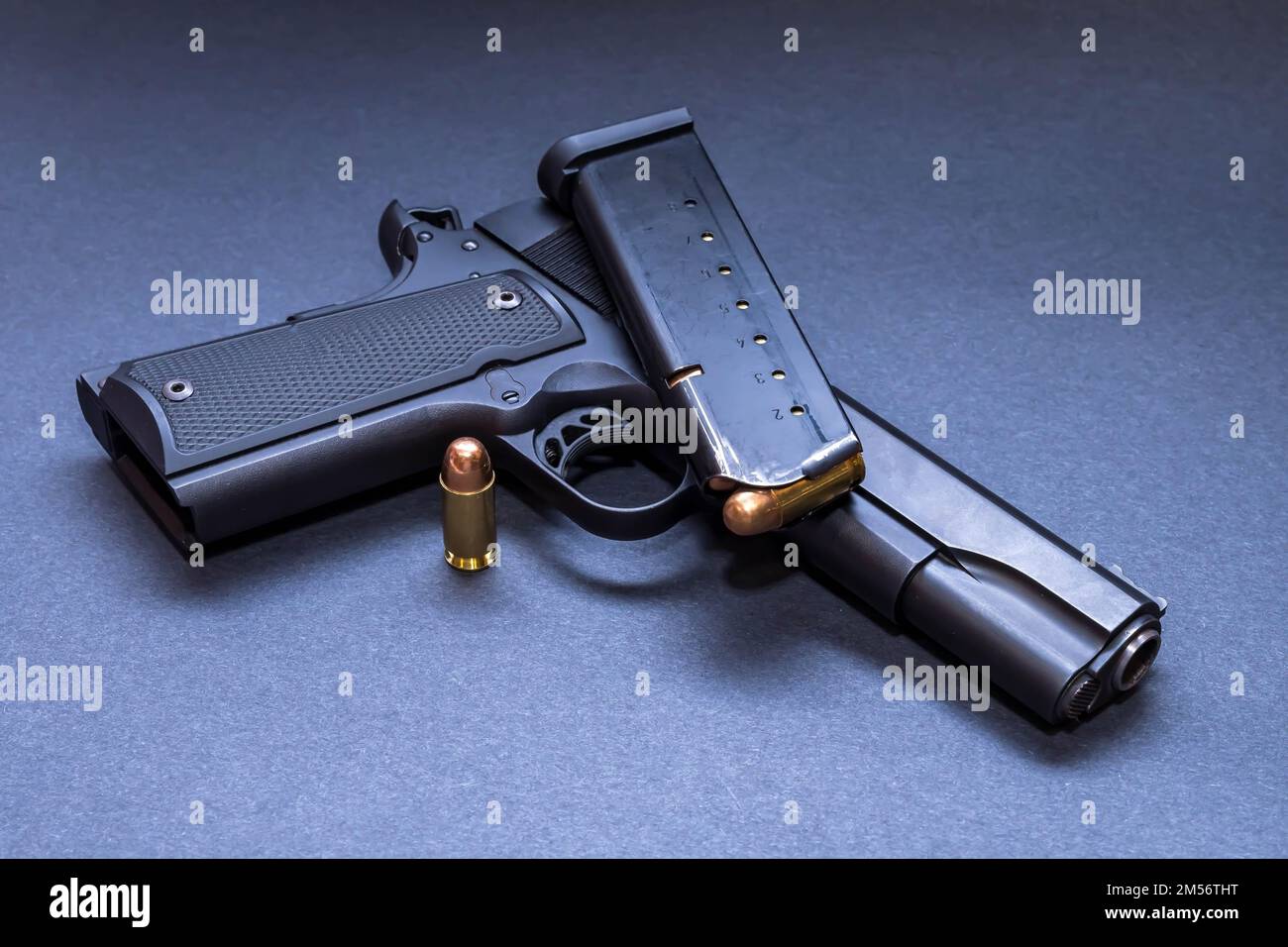 A 45 caliber 1911 model pistol with a loaded magazine on top of it and ...