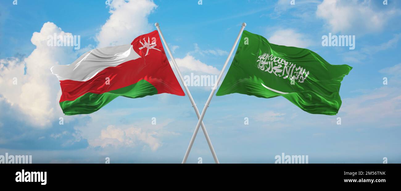 two crossed flags Saudi Arabia and Oman waving in wind at cloudy sky ...