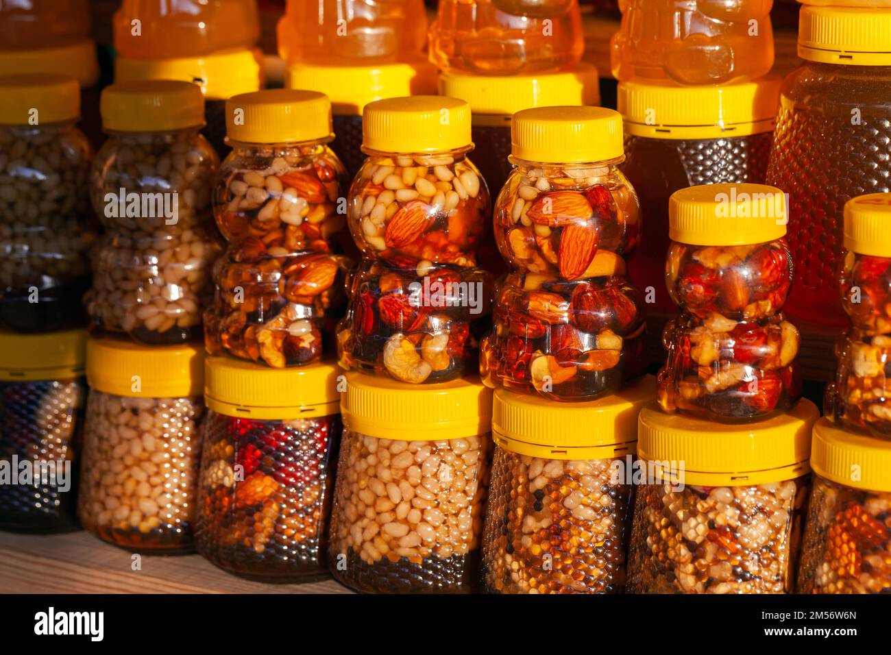 Assortment of honey with nuts in plastic jars. Close up photo with ...
