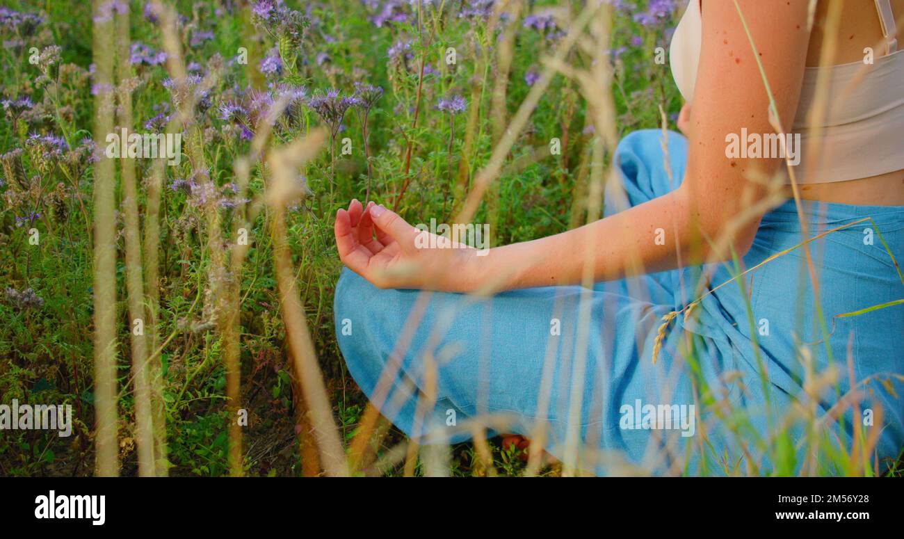 Meditation on flowers field. Woman relaxing. Lotus position. Breathing ...